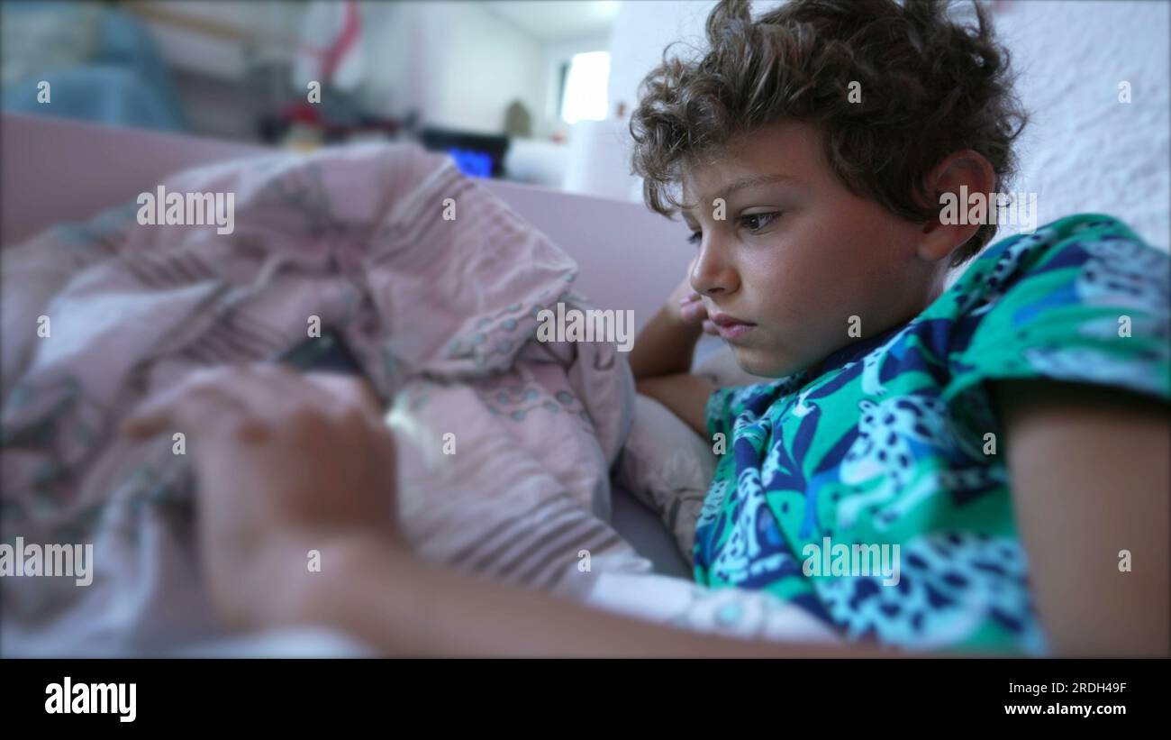Young boy watching entertainment media with phone in bed Stock Photo ...