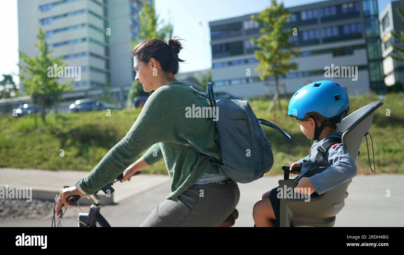 Mother riding bicycle with little boy sitting on back seat Stock Photo ...