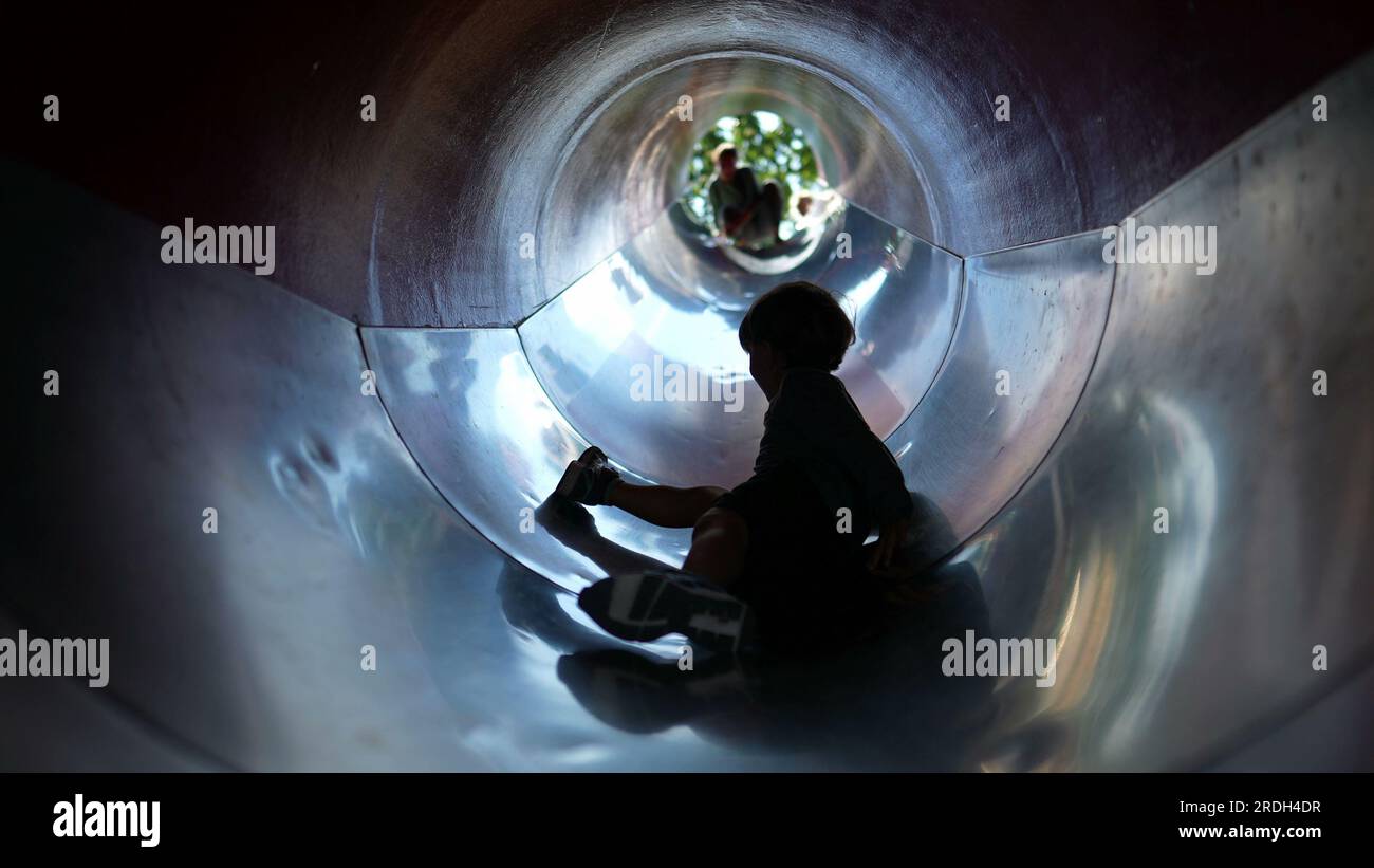One fun kid sliding down inside tunner slider at playground Stock Photo ...