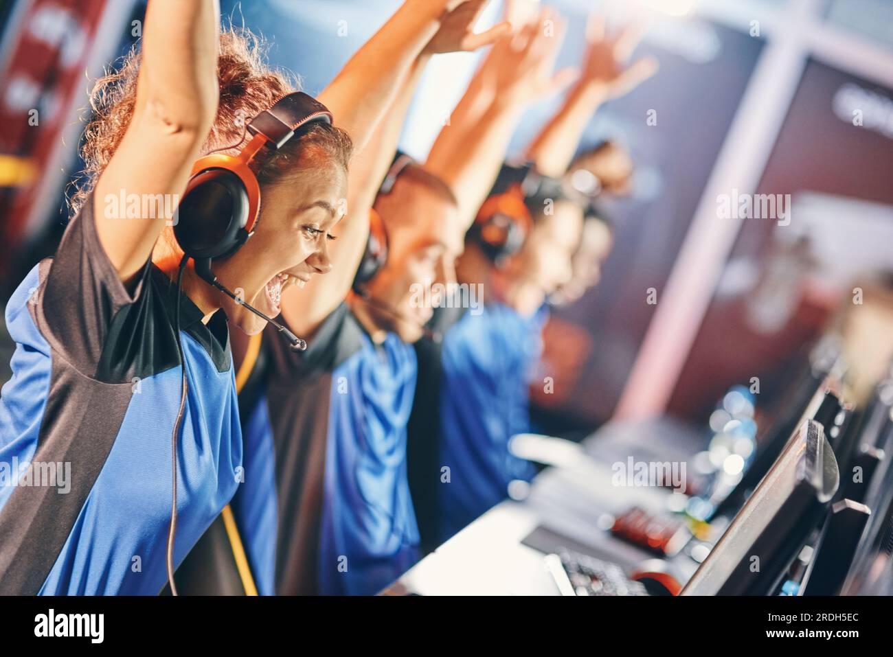 Side view of a excited mixed race girl, female cybersport gamer raising ...