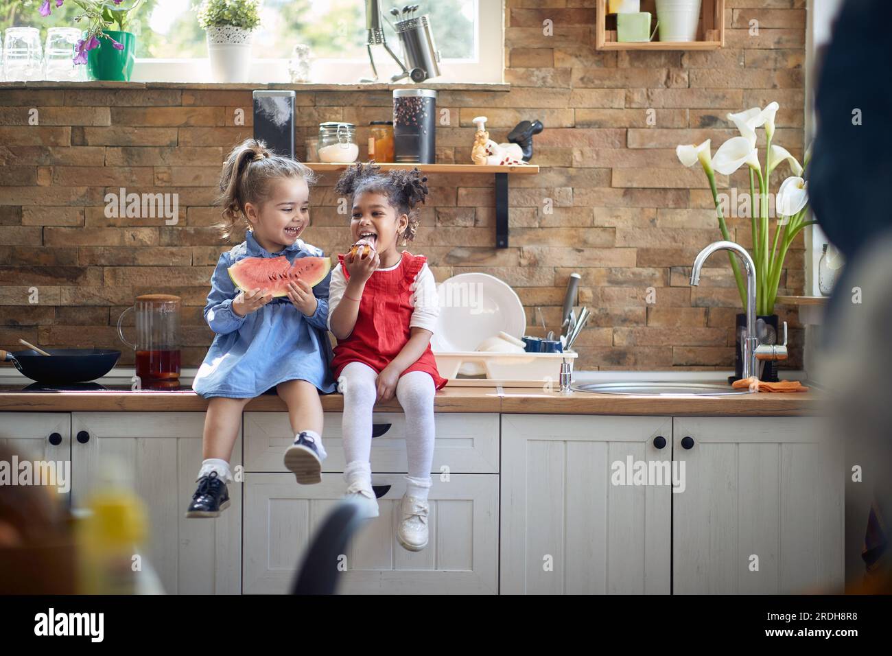 Two toddler girls come together.One girl takes a bite of a delectable ...