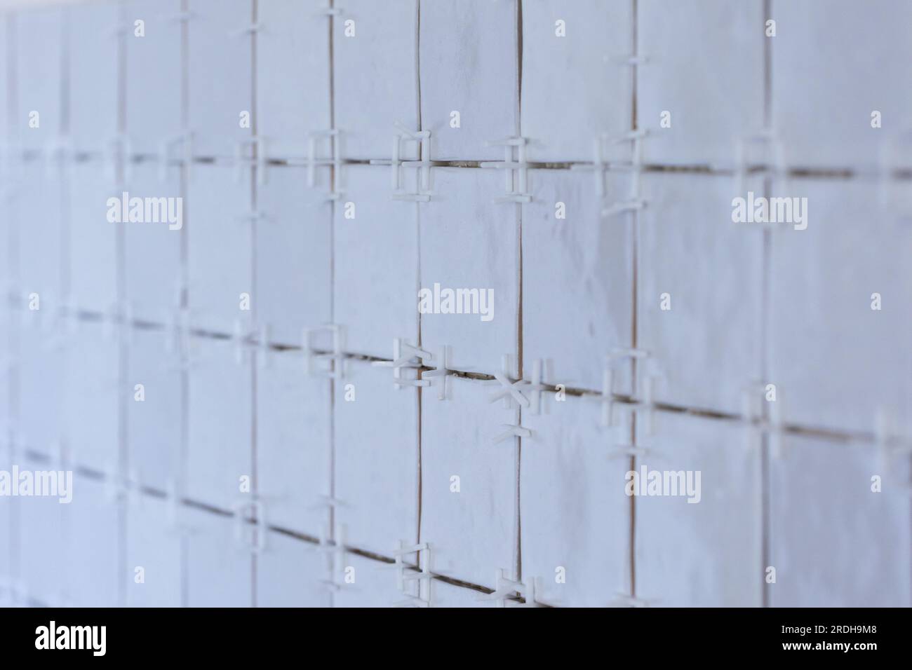 A portrait of a tile wall under construction. The wall is being tiled ...