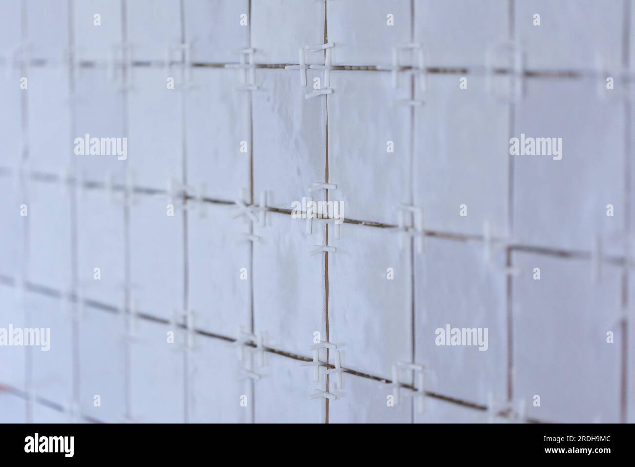 A portrait of a tile wall under construction. The wall is being tiled ...