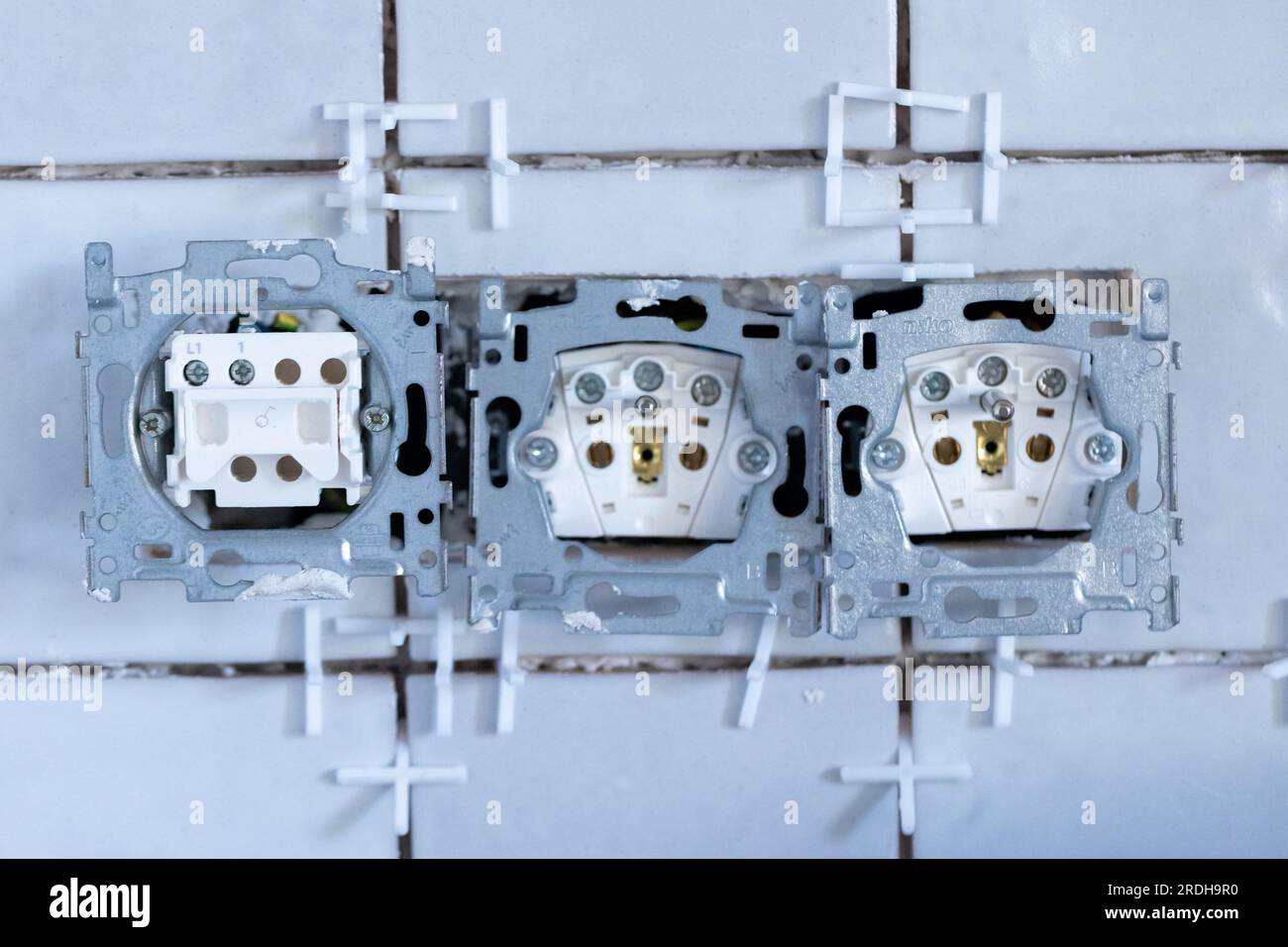 A close up portrait of two electric wall sockets and one light switch ...