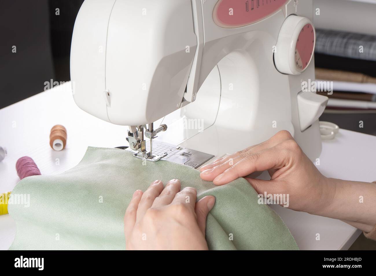 Female hands stitching green fabric on modern sewing machine at ...