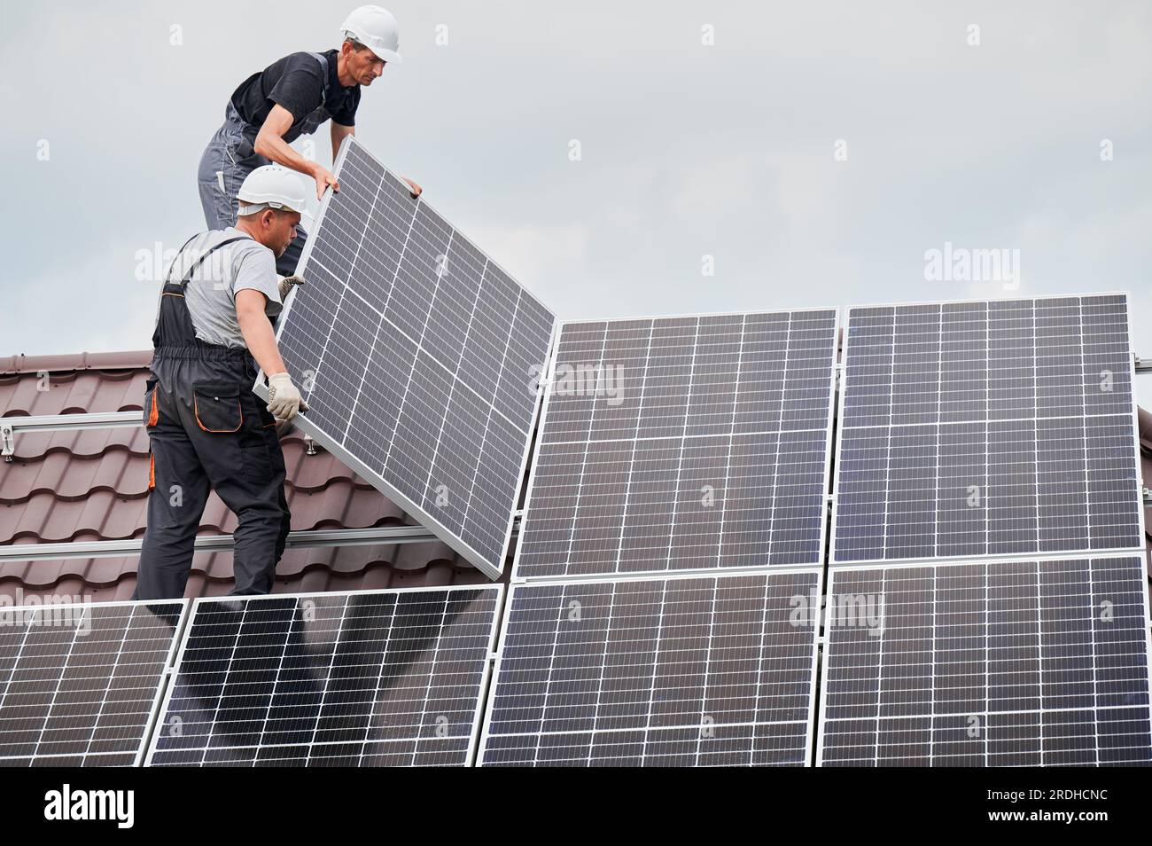 Men technicians mounting photovoltaic solar moduls on roof of house ...