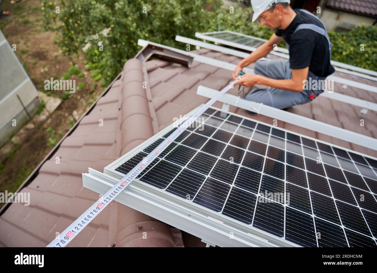 Man measuring photovoltaic solar panels with tape measure. Male worker ...