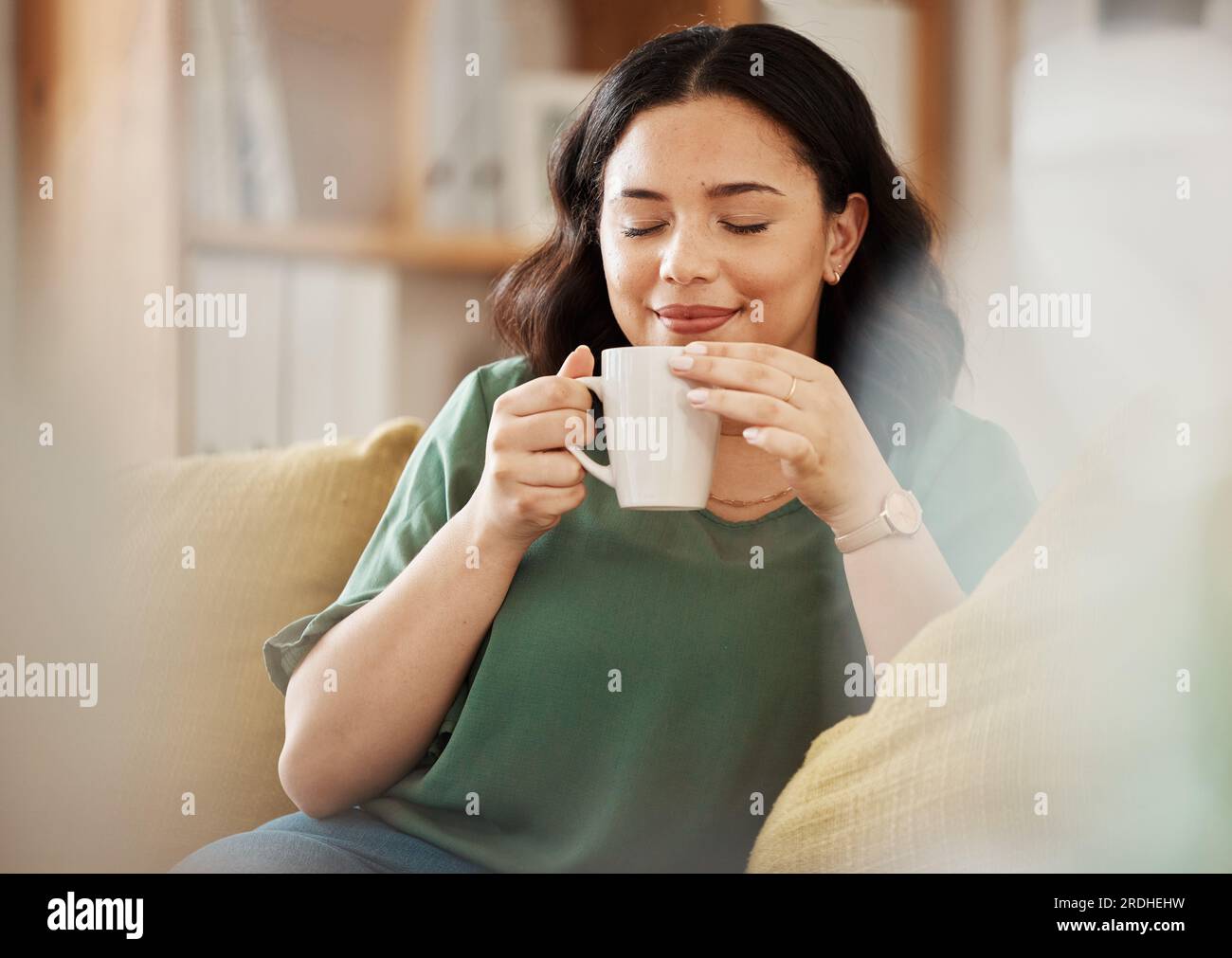 Tea, relax and smile with a woman in her home, sitting on a sofa in the ...