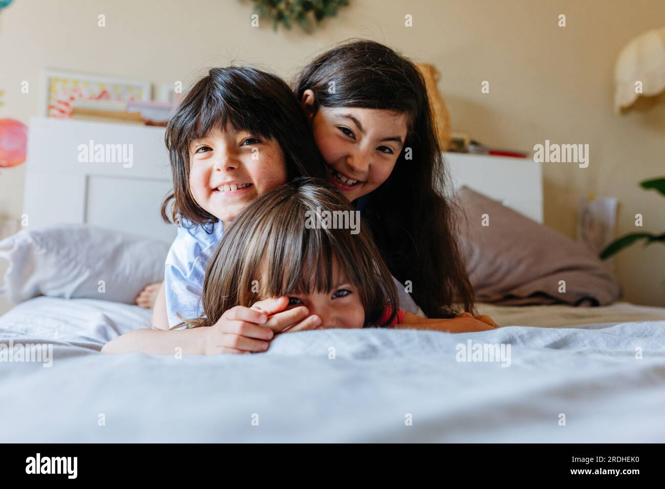 pyramid of three smiling children lying on each other on the bed Stock ...