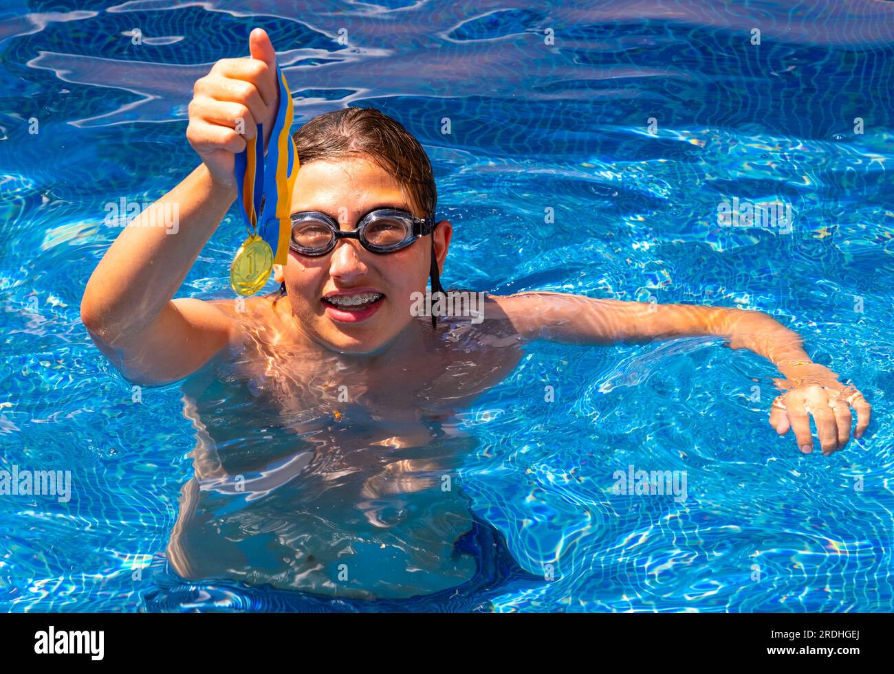 Successful caucasian young swimmer with award in outdoor pool. Golden ...
