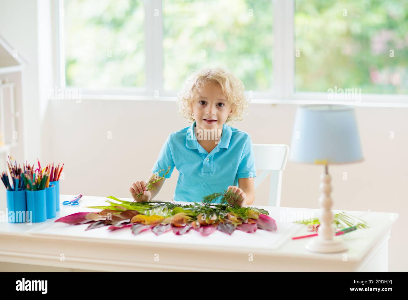 Child creating picture with colorful leaves. Art and crafts for kids ...