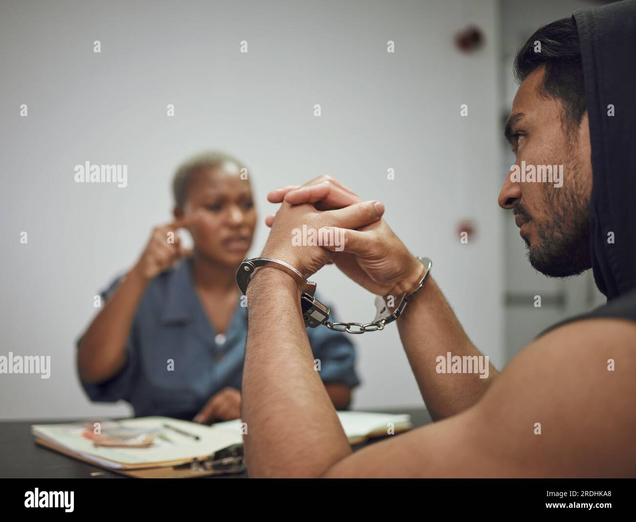 Crime, suspect and female police officer at the station writing a legal ...