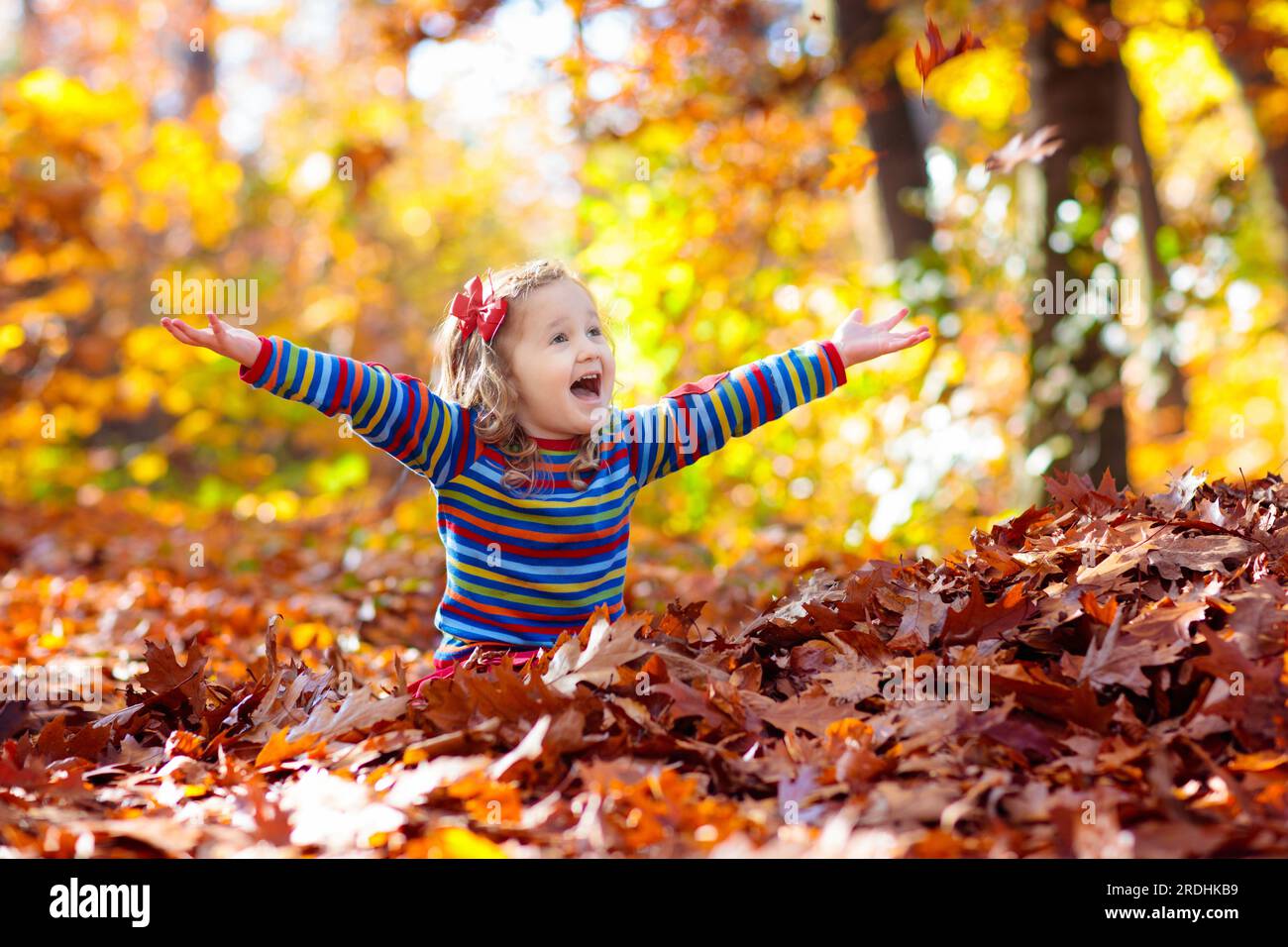 Child in autumn park. Little girl with yellow leaf. Kid playing with ...