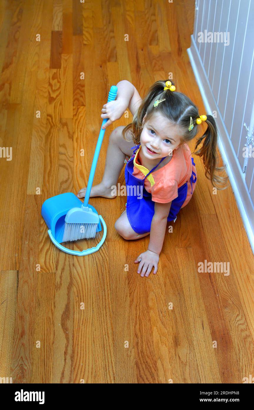 Willing helper is learning to do household chores. She is holding a ...