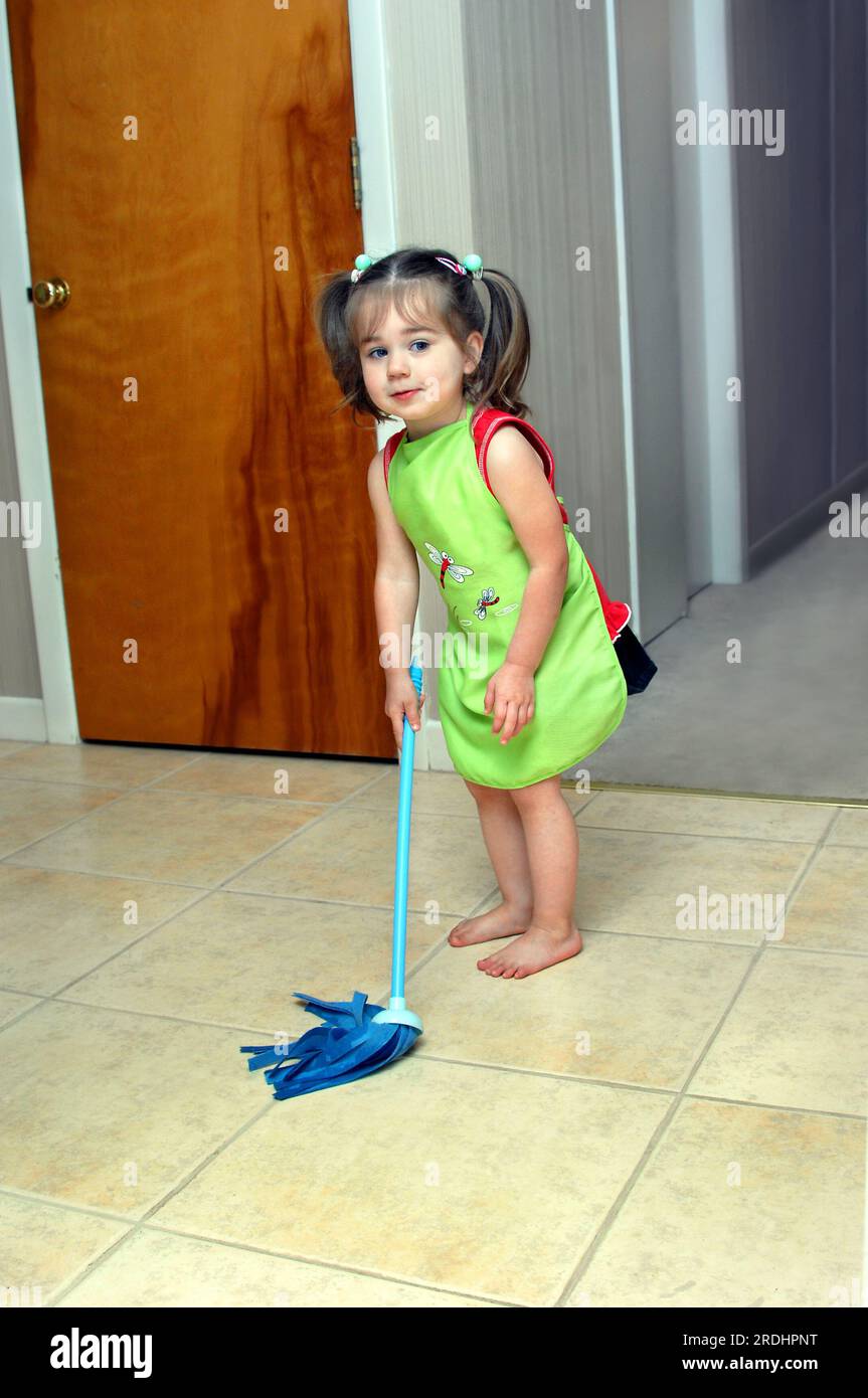 Little girl learns the lesson of hard work. She is holding a blue, play ...