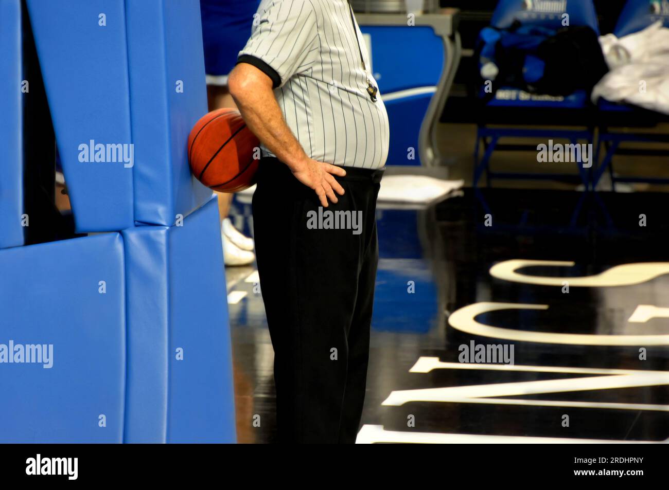 Referee during a basketball time-out, leans against goal and uses the ...