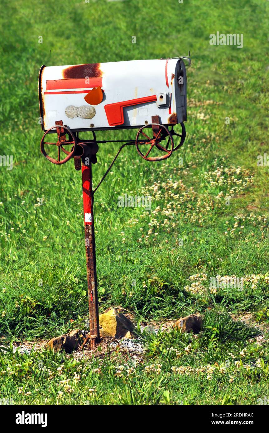 Rustic, rural mailbox stands on grassy knoll. Shaped like an American ...