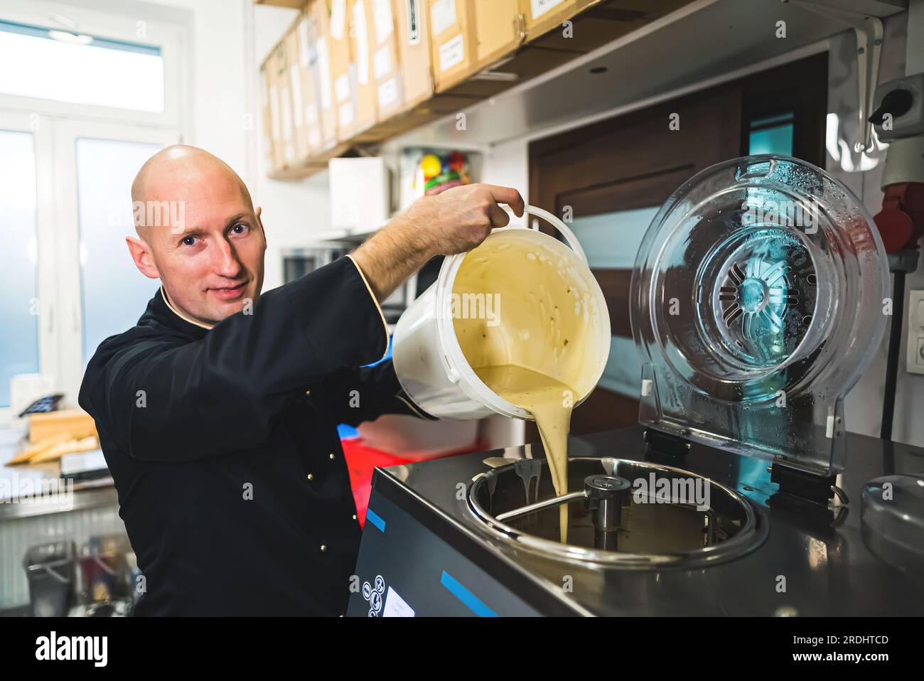 Chef pouring ice cream into ice cream into big steel ice cream machine ...