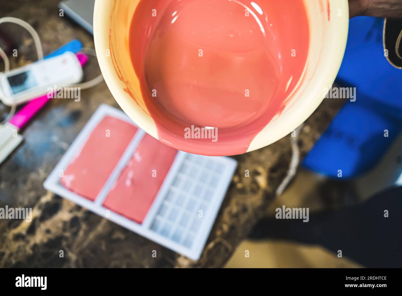 Closeup of melted ruby chocolate poured into white chocolate bar moulds ...