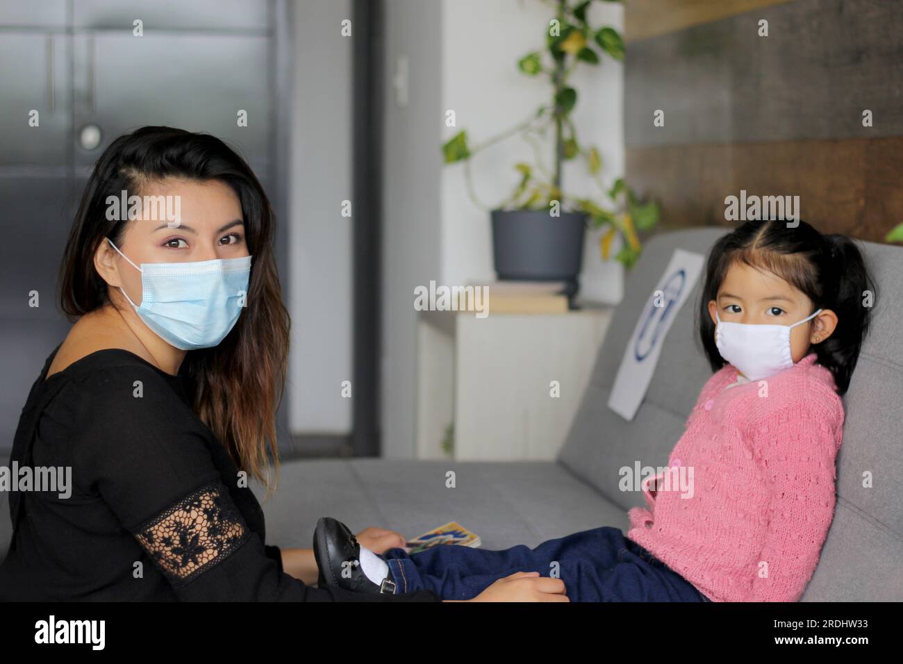 Latin mom and 3 year old girl with protective face masks and backpack ...