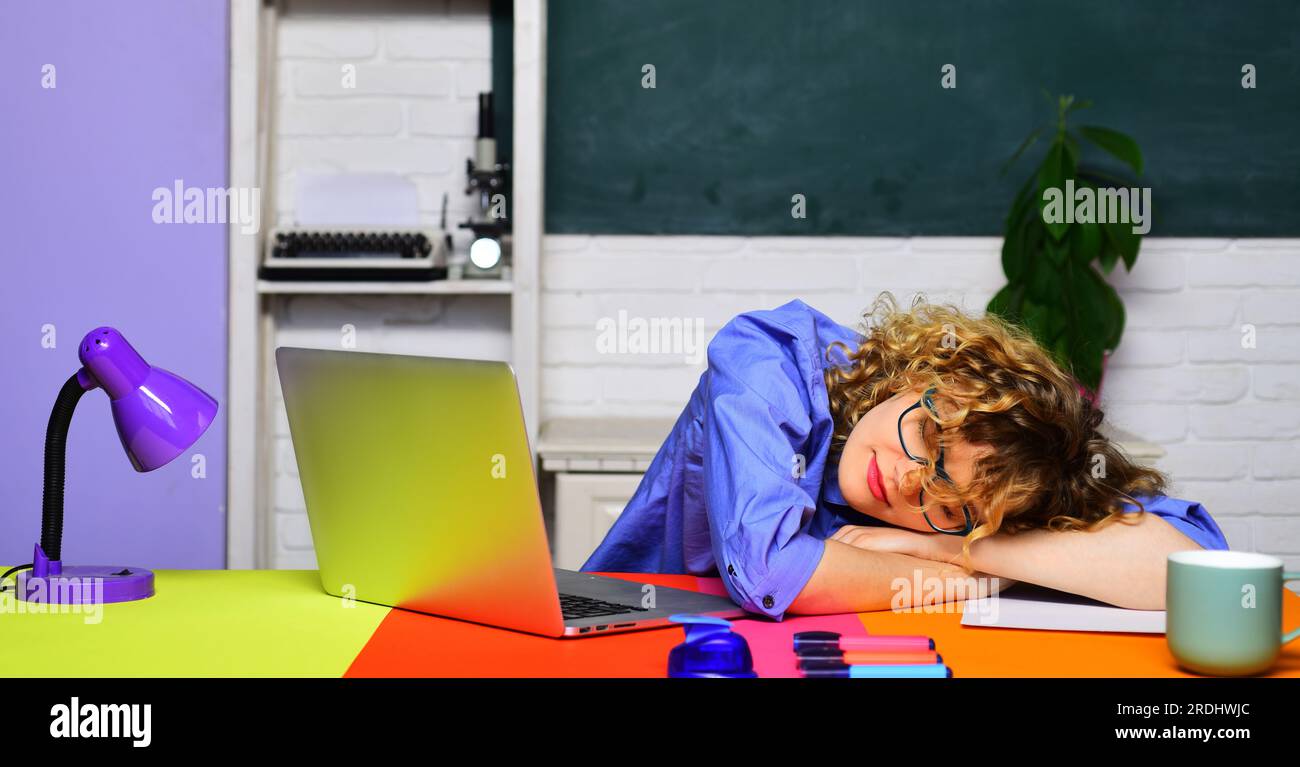 Tired female teacher in glasses sleeping at desk in classroom. Back to ...