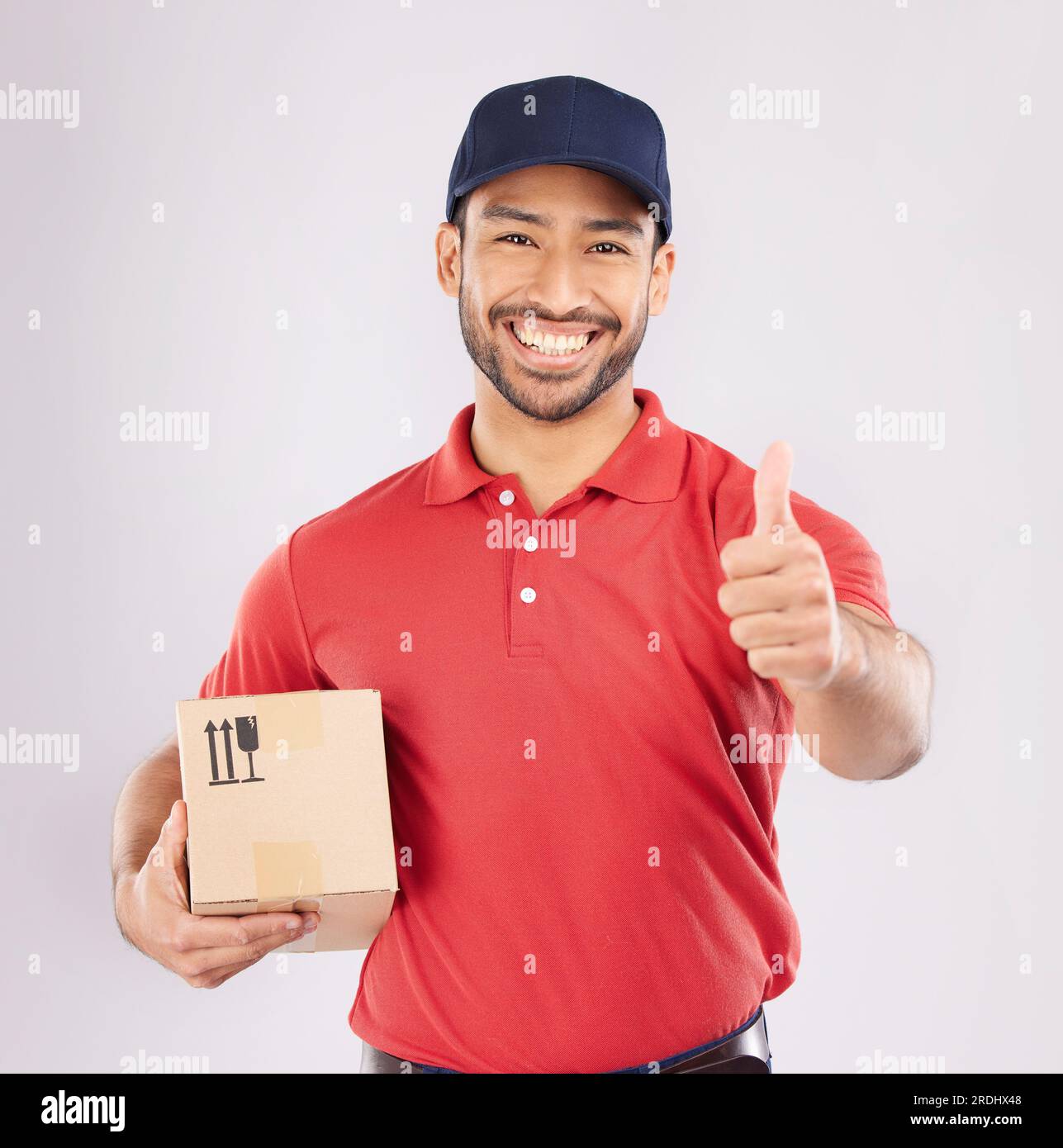Courier man, thumbs up and studio portrait with box, delivery company ...
