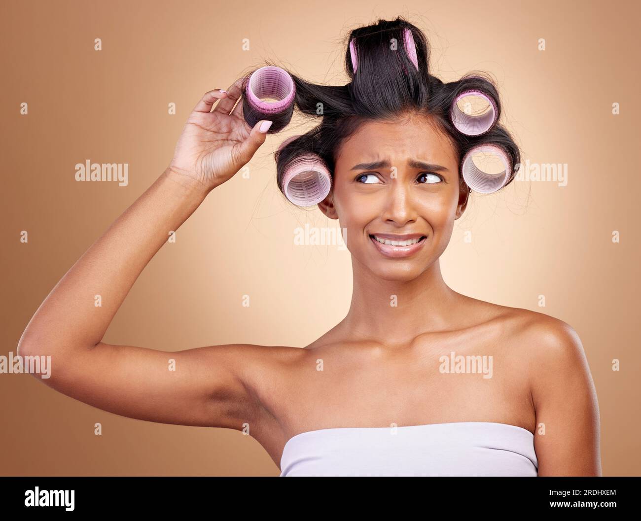 Hair care, problem and a woman with rollers on a studio background for ...