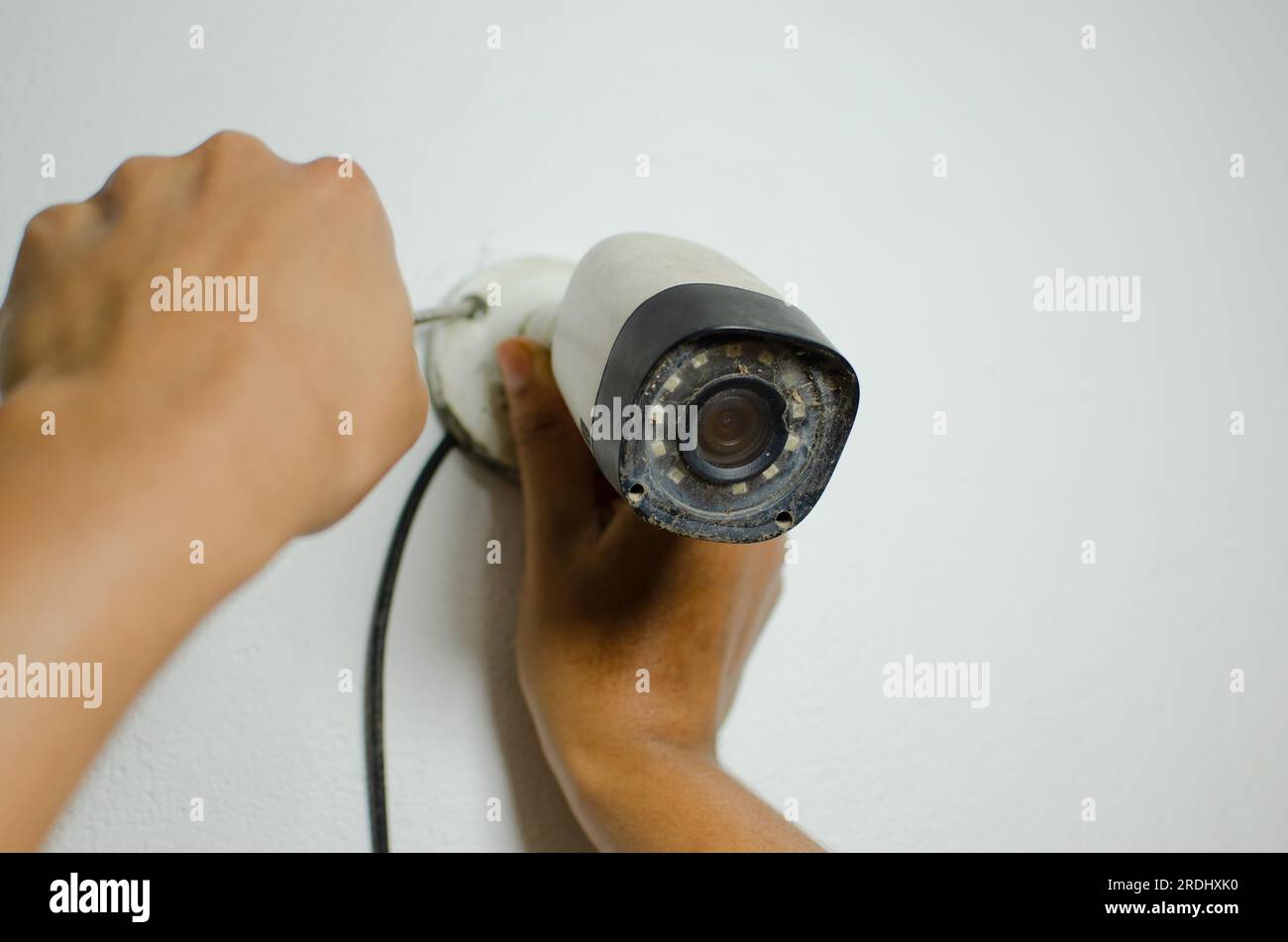 Skilled professional maintaining a white security camera to enhance ...