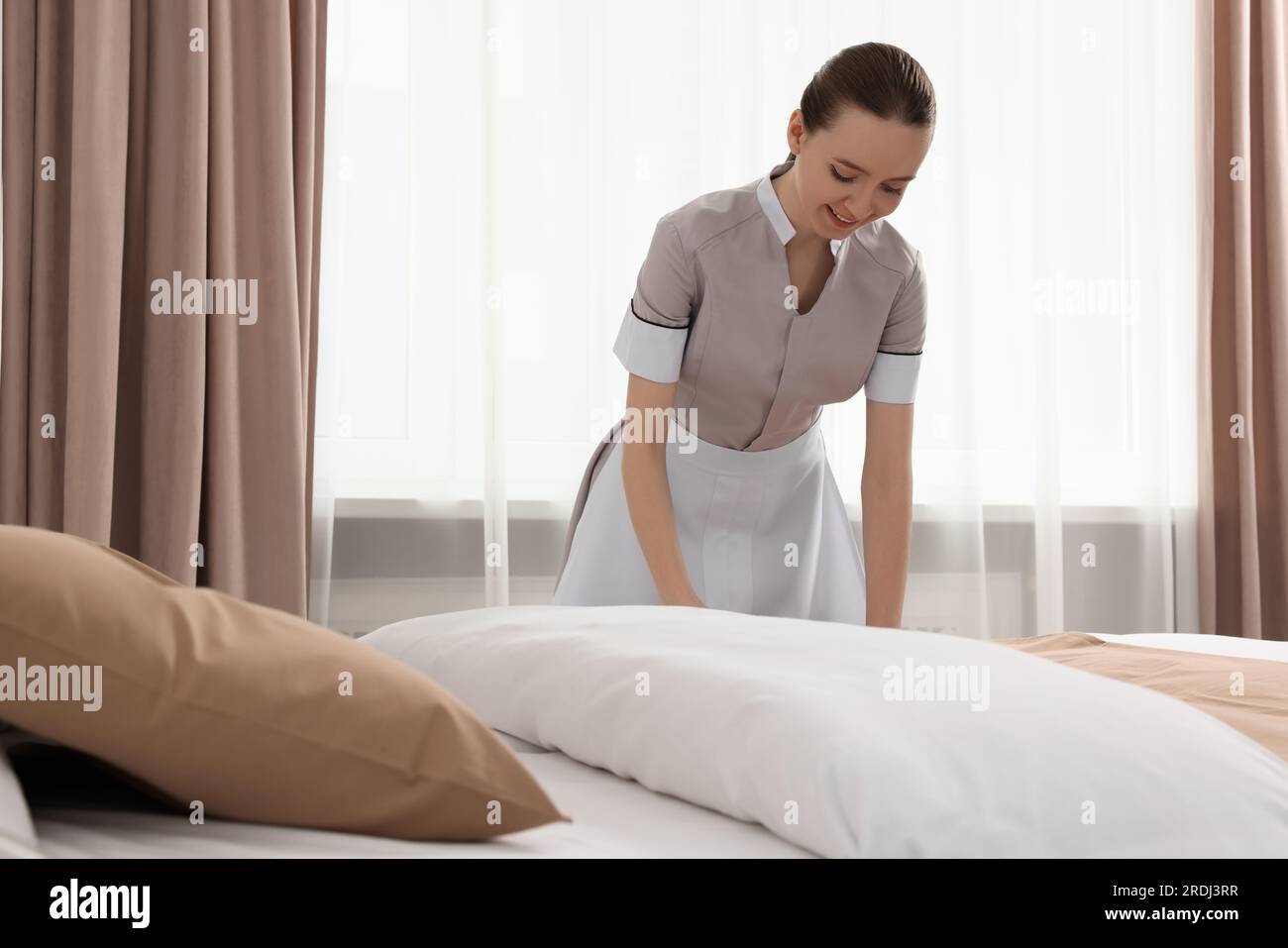 Young maid making bed in hotel room Stock Photo - Alamy