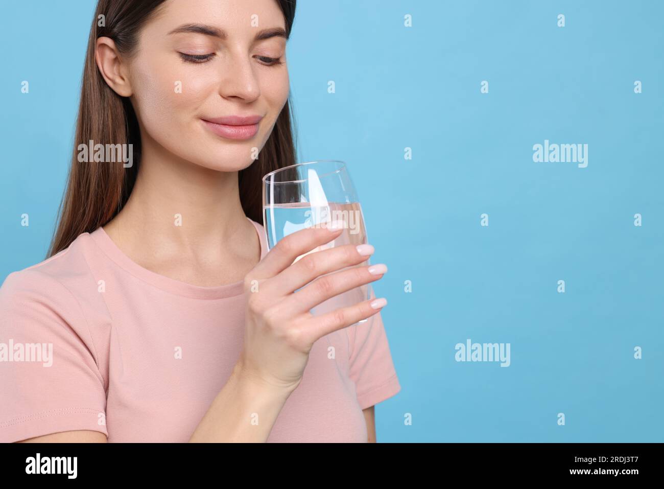 Healthy habit. Woman holding glass with fresh water on light blue ...