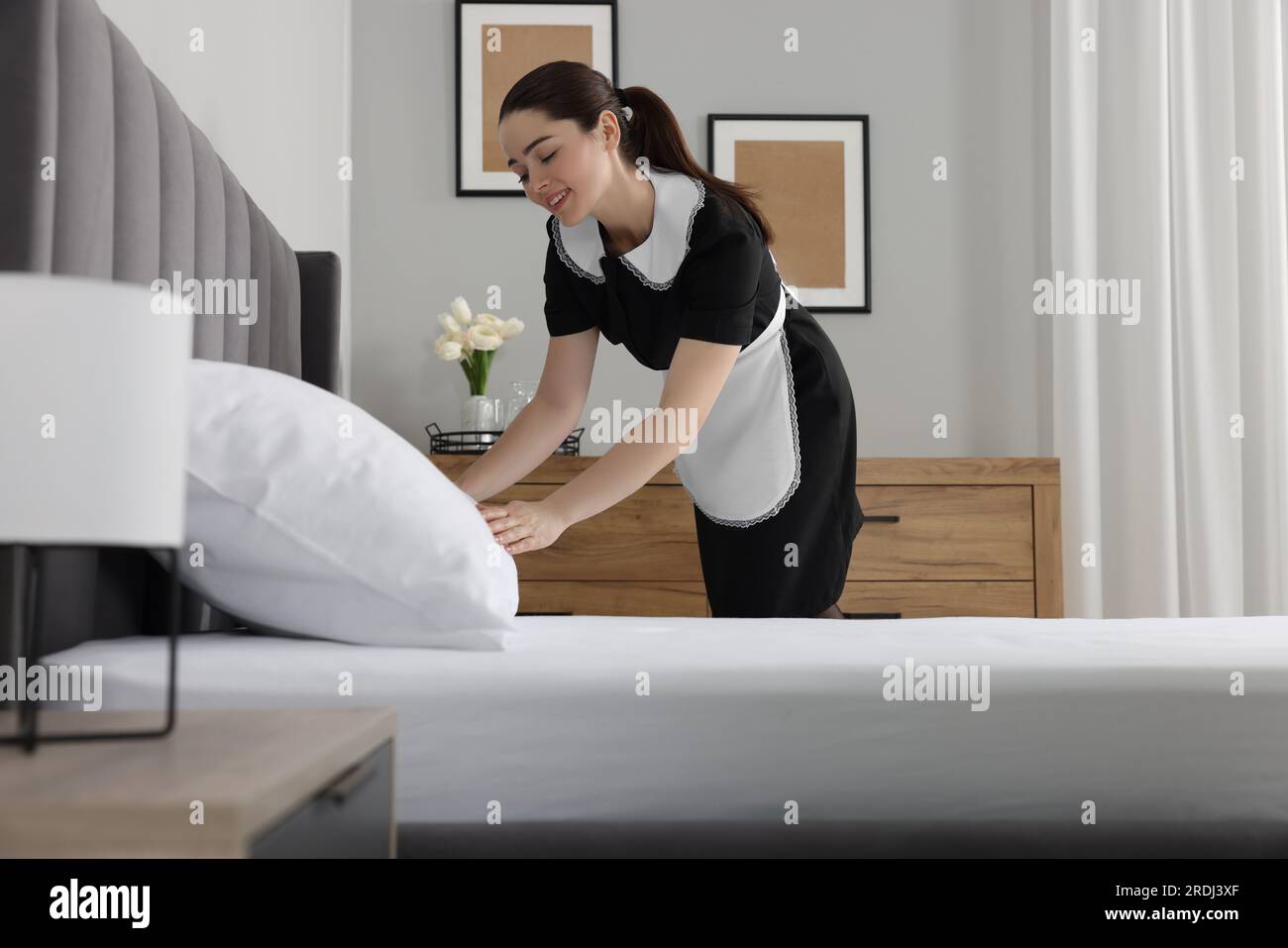 Young chambermaid making bed in hotel room Stock Photo - Alamy