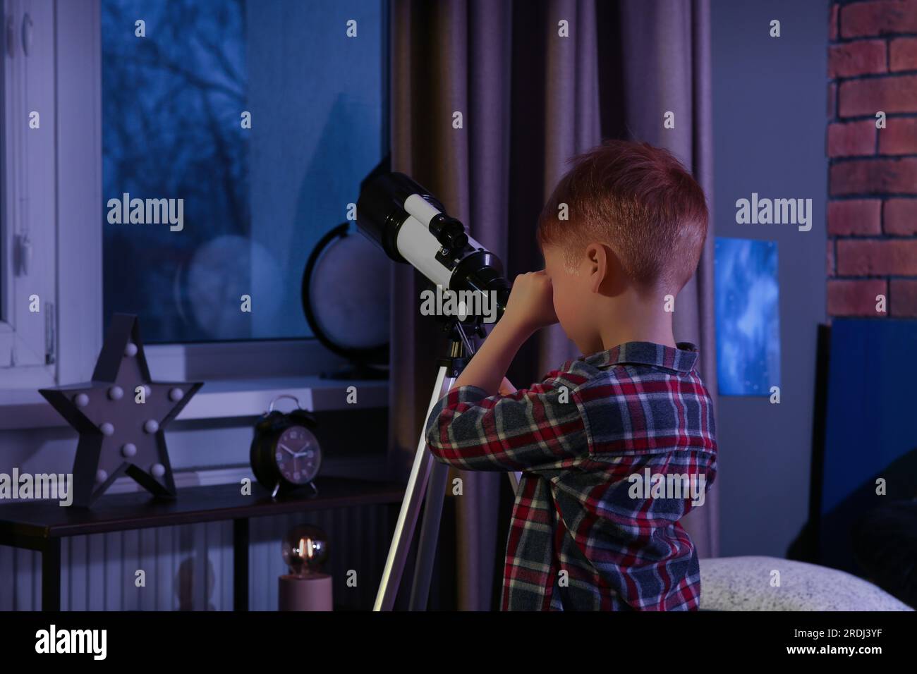 Little boy looking at stars through telescope in room, back view Stock ...