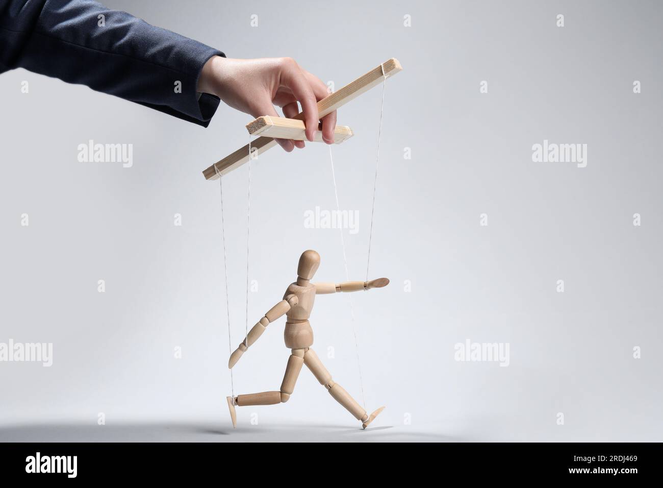 Woman pulling strings of puppet on light grey background, closeup ...
