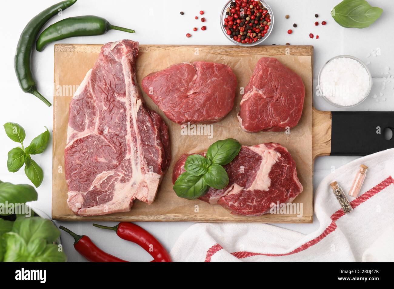 Flat lay composition with cut fresh beef meat and spices on white table ...