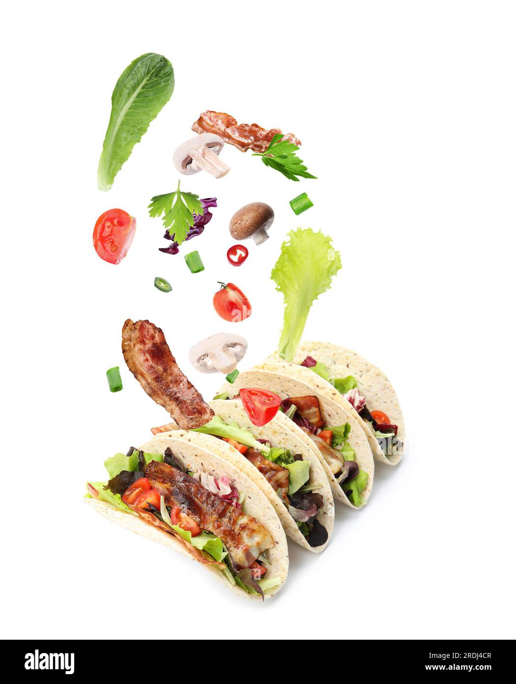Delicious tacos. Ingredients falling into tortillas on white background ...