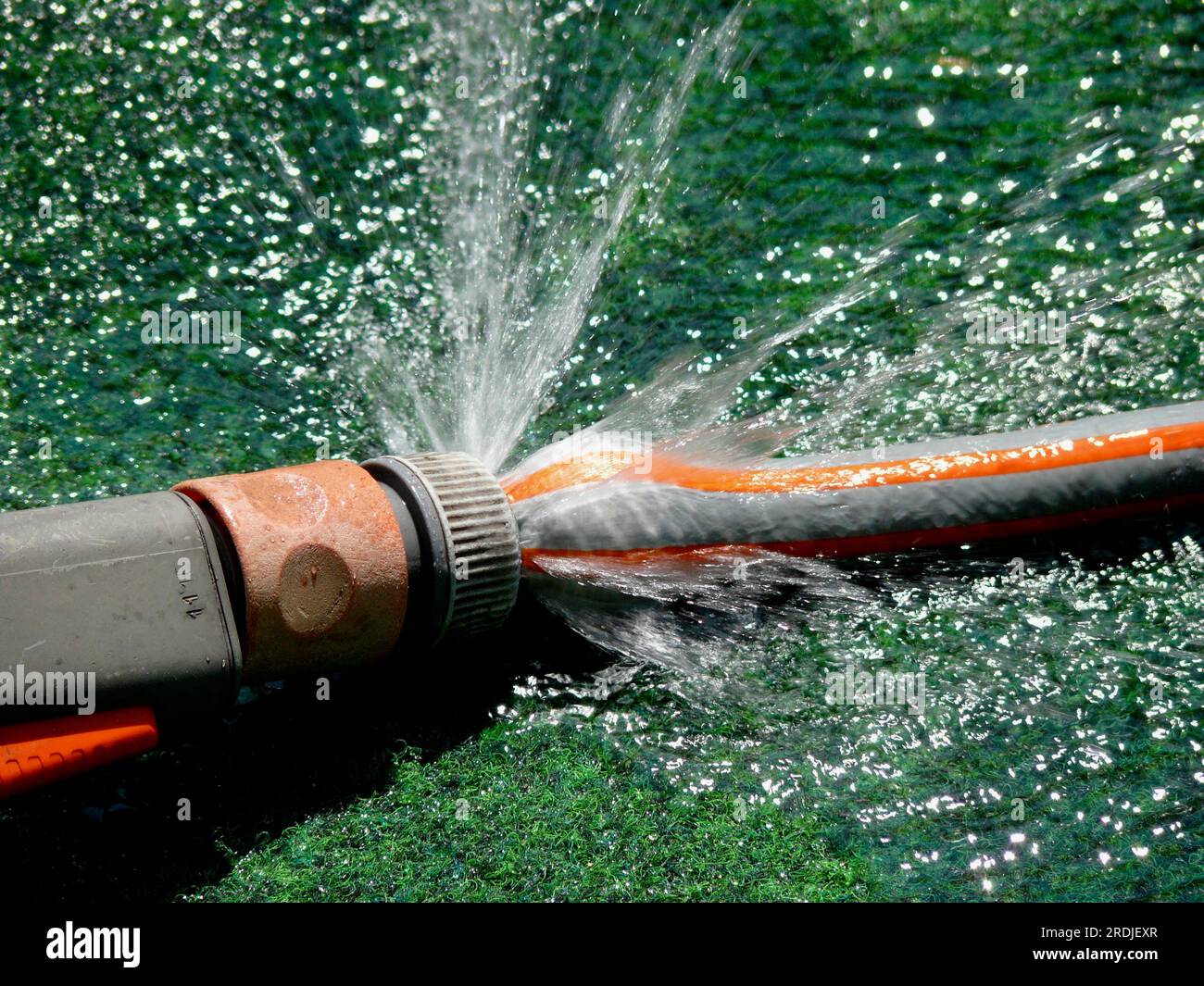 Leaking garden hose, splashing water Stock Photo - Alamy