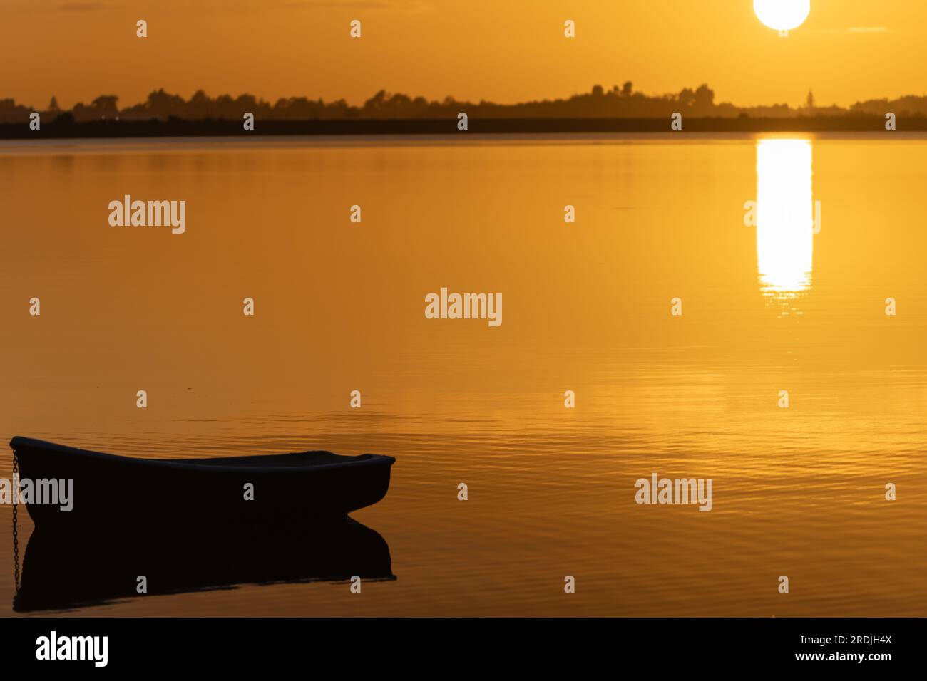Golden sunrise with glow of round sun rising above horizon across bay ...