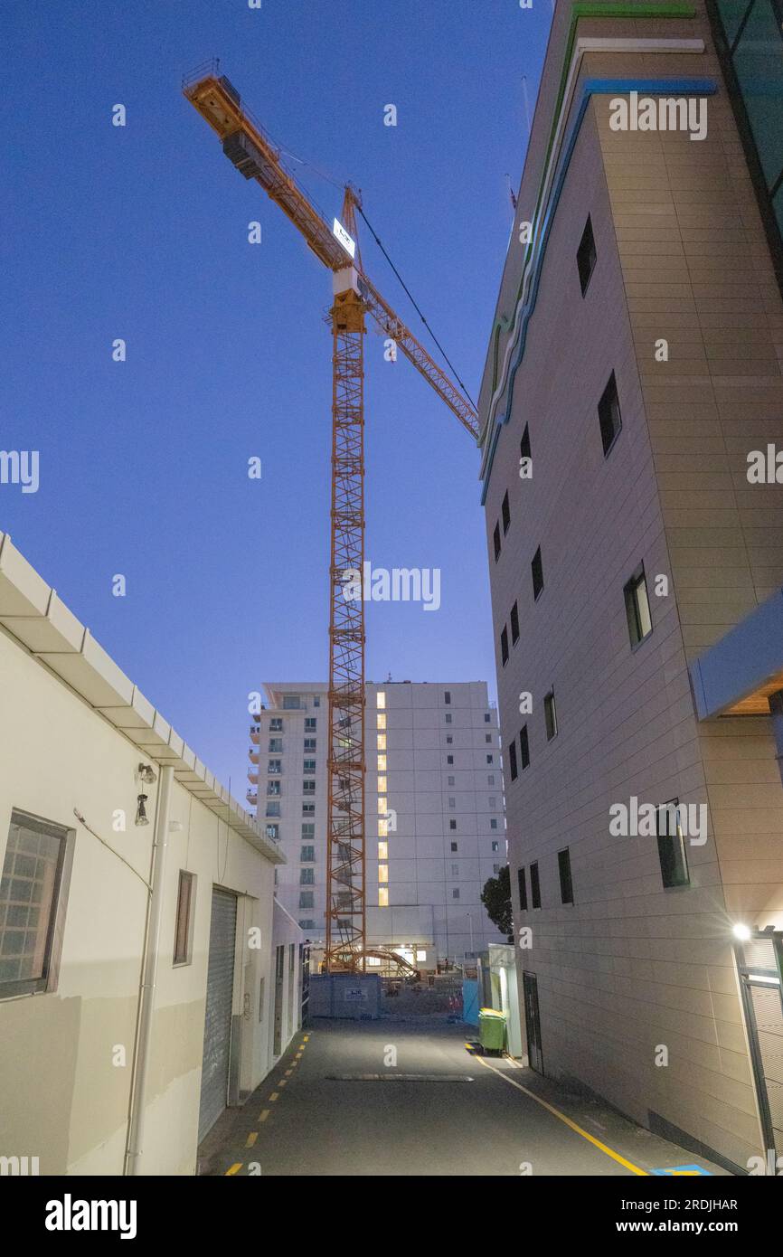 Tall construction crane in Tauranga city at end of alley between ...