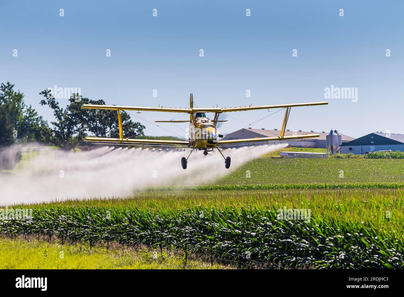 A crop duster applies chemicals to a field of vegetation Stock Photo ...