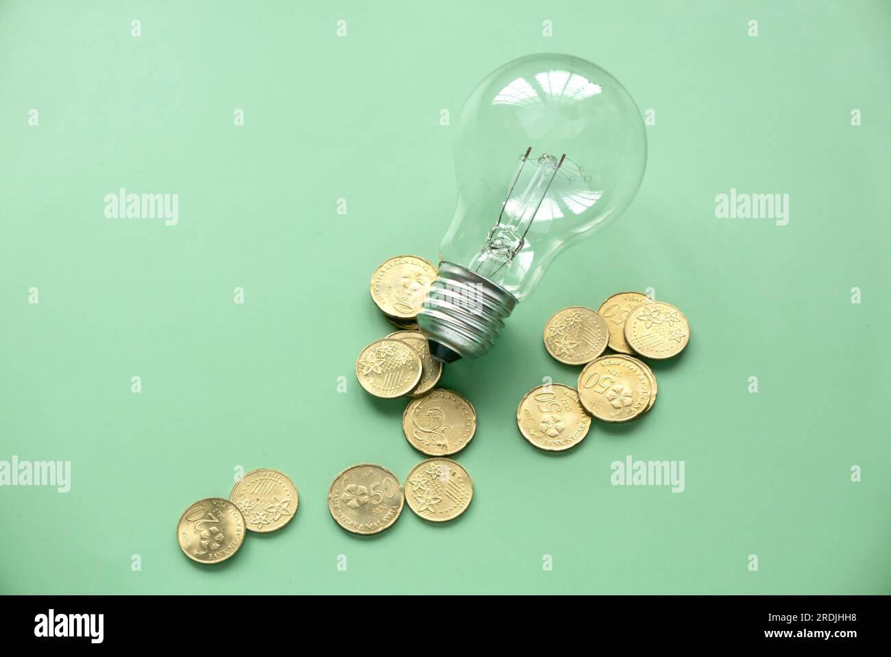 Light bulb and the gold coins on the green background.The concept of ...