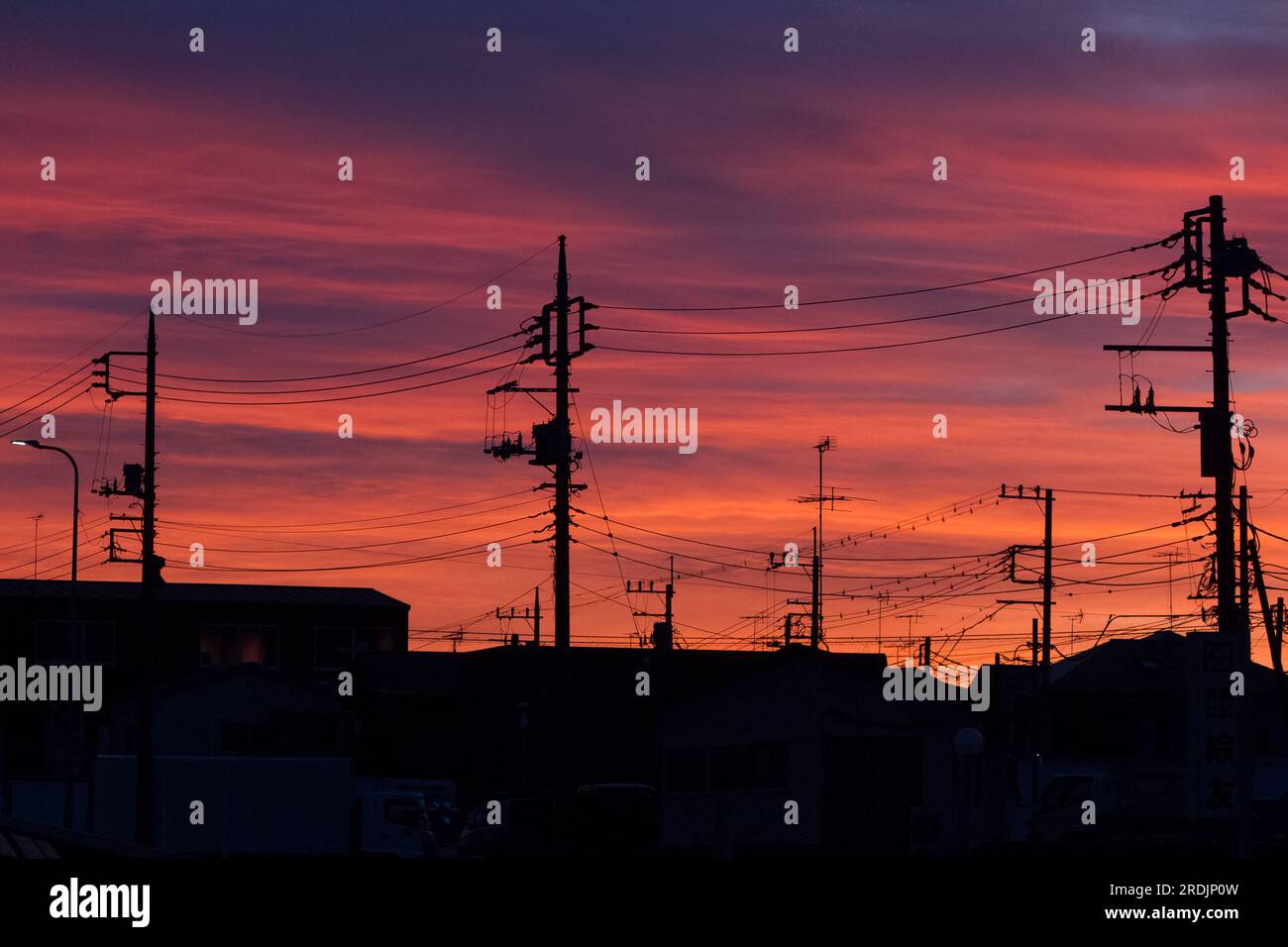 A colourful dawn sky over buildings and telegraph poles in Tsuruma ...
