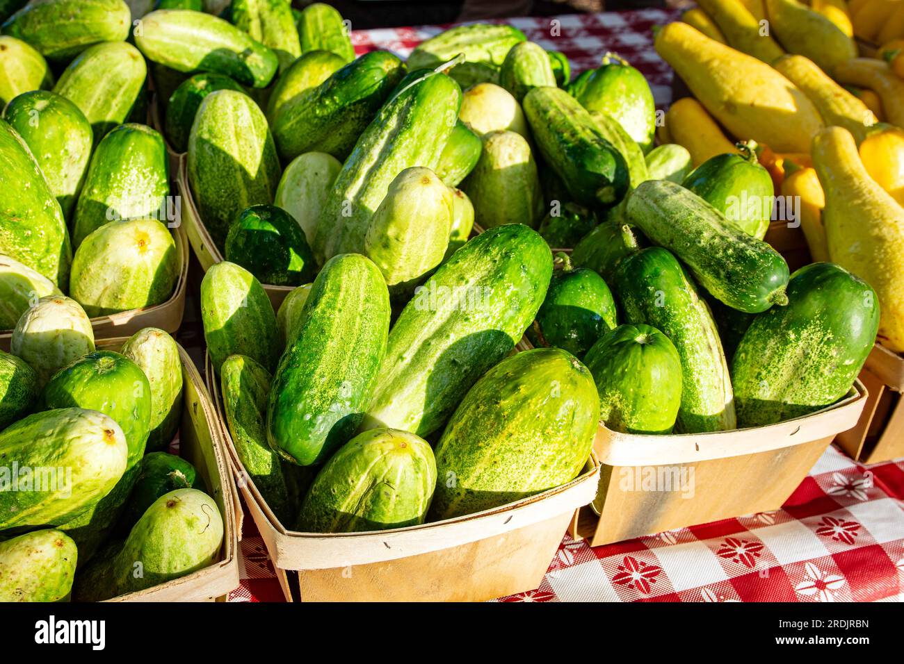 Baskets of cucumbers and crookneck squash in wooden cartons on a ...