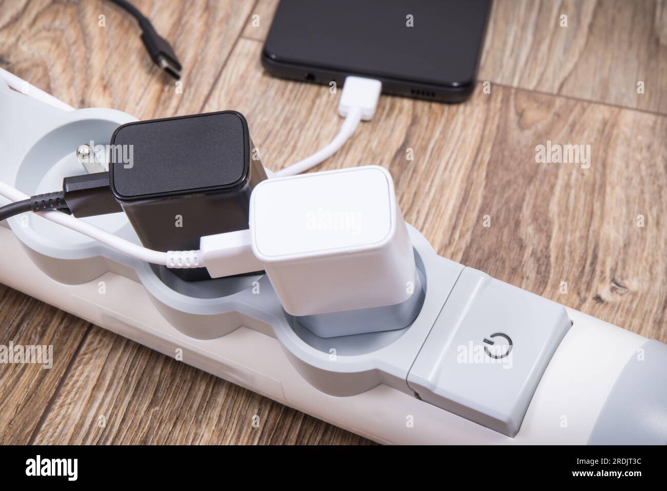 Smartphone, mobile phone and chargers connected to electrical power ...