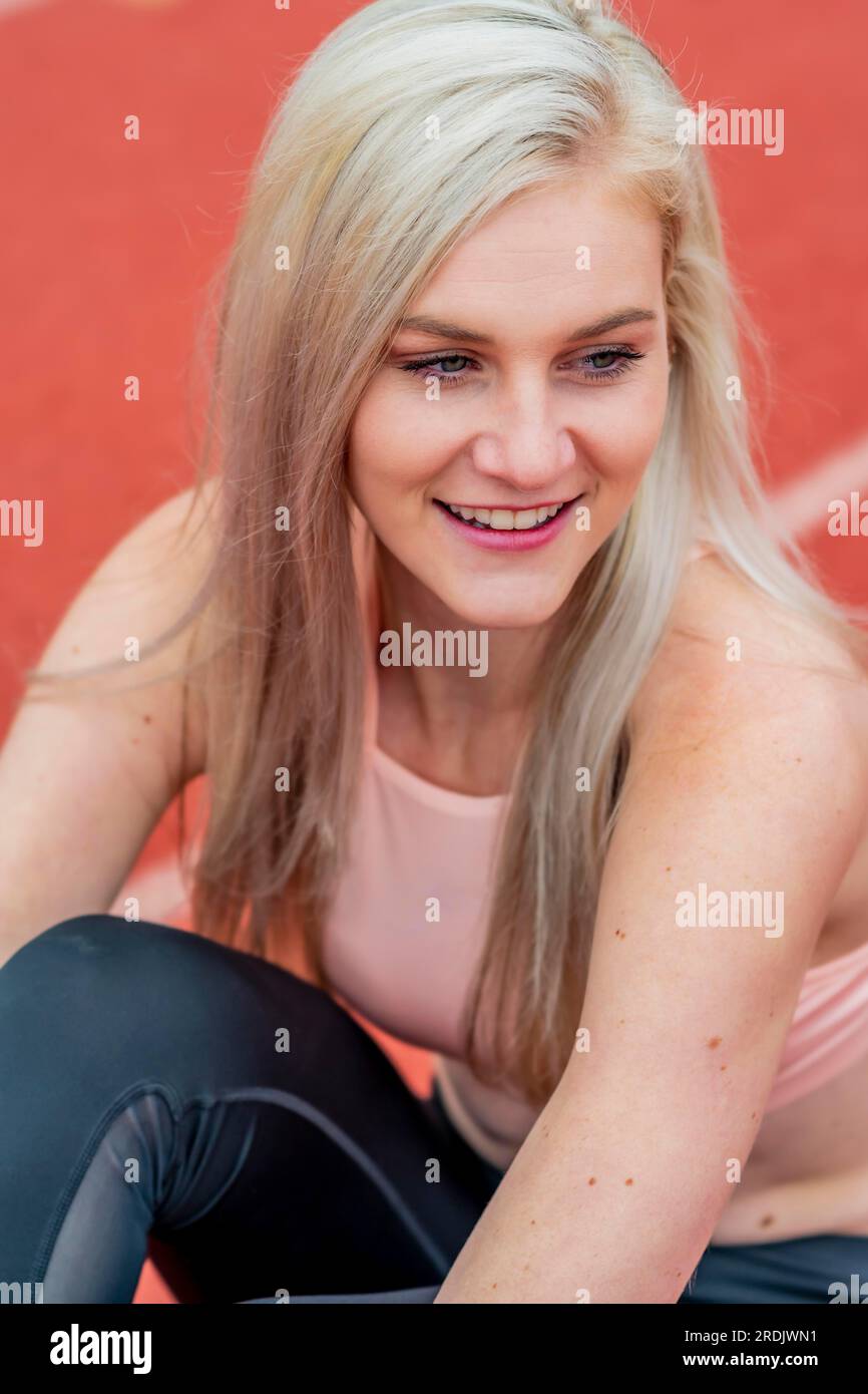 A beautiful young college athlete prepares herself for a track meet at ...