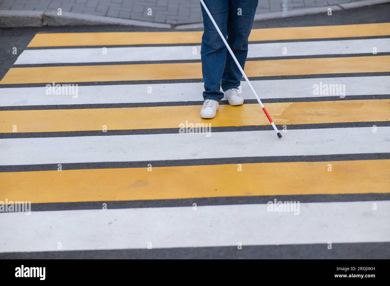 Close-up of the legs of a blind woman crossing the road at a crosswalk ...
