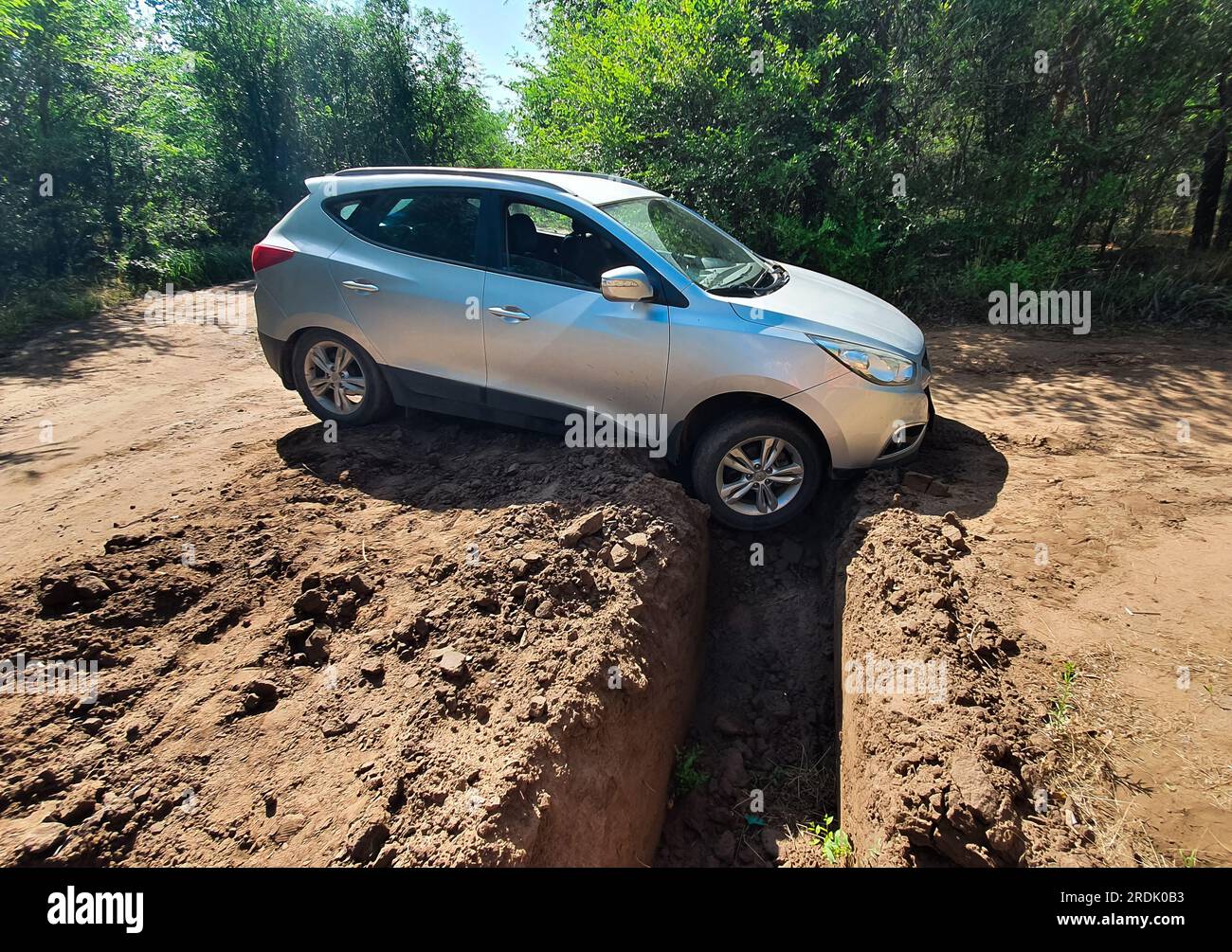 The car hit the front wheel in a deep hole on the road in the forest ...