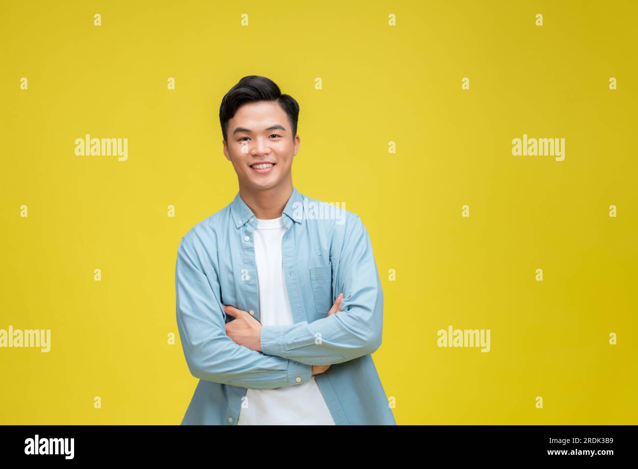 Smiling asian guy looking happy at camera, cross arms chest confident ...
