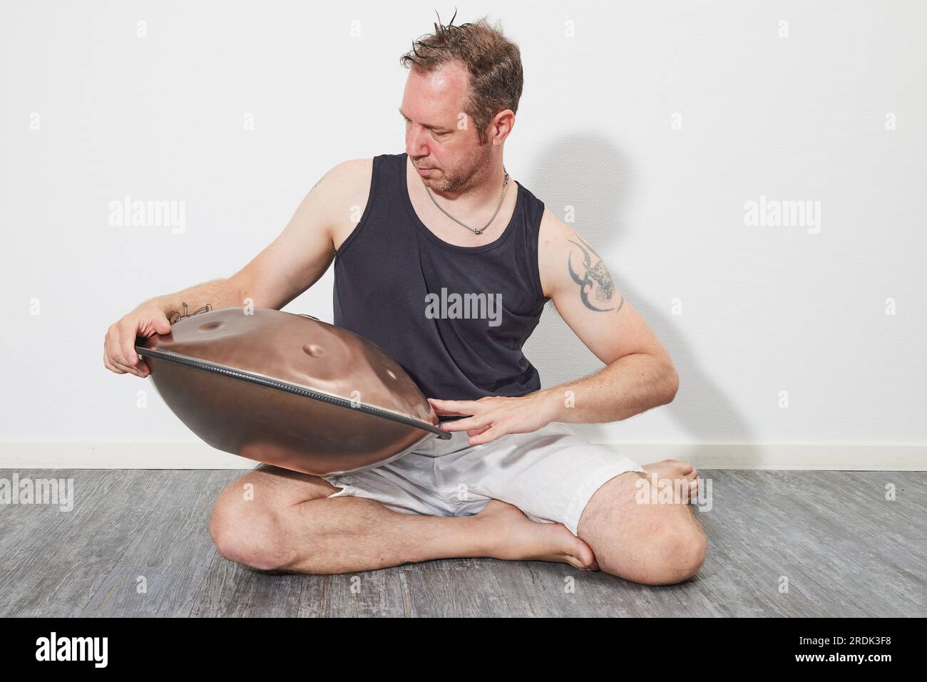 Man sitting on floor playing handpan Stock Photo - Alamy