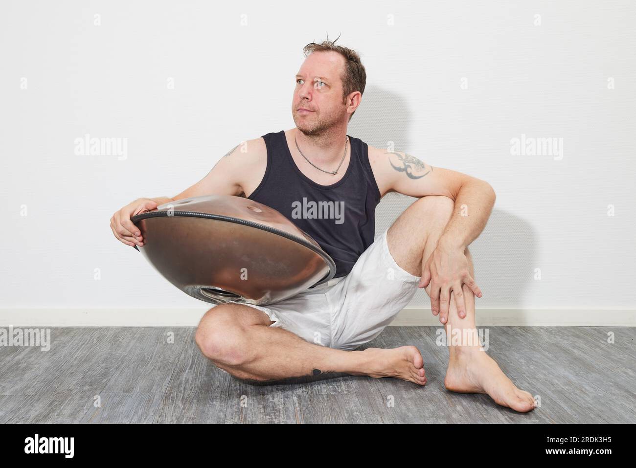 Man sitting on floor playing handpan Stock Photo - Alamy