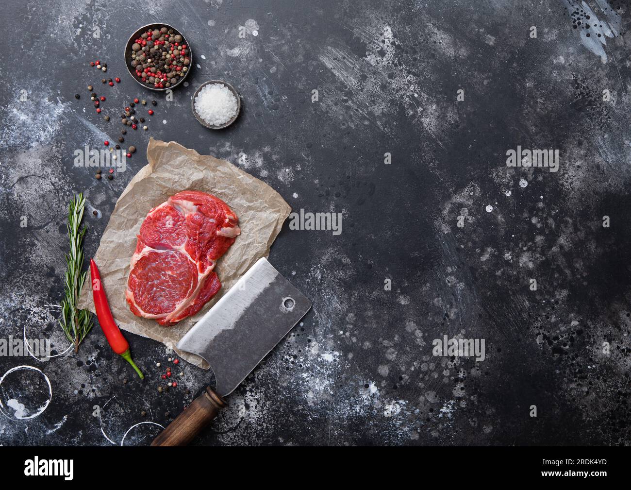 Piece of raw red rib eye beef fillet with steel cleaver,salt and pepper ...